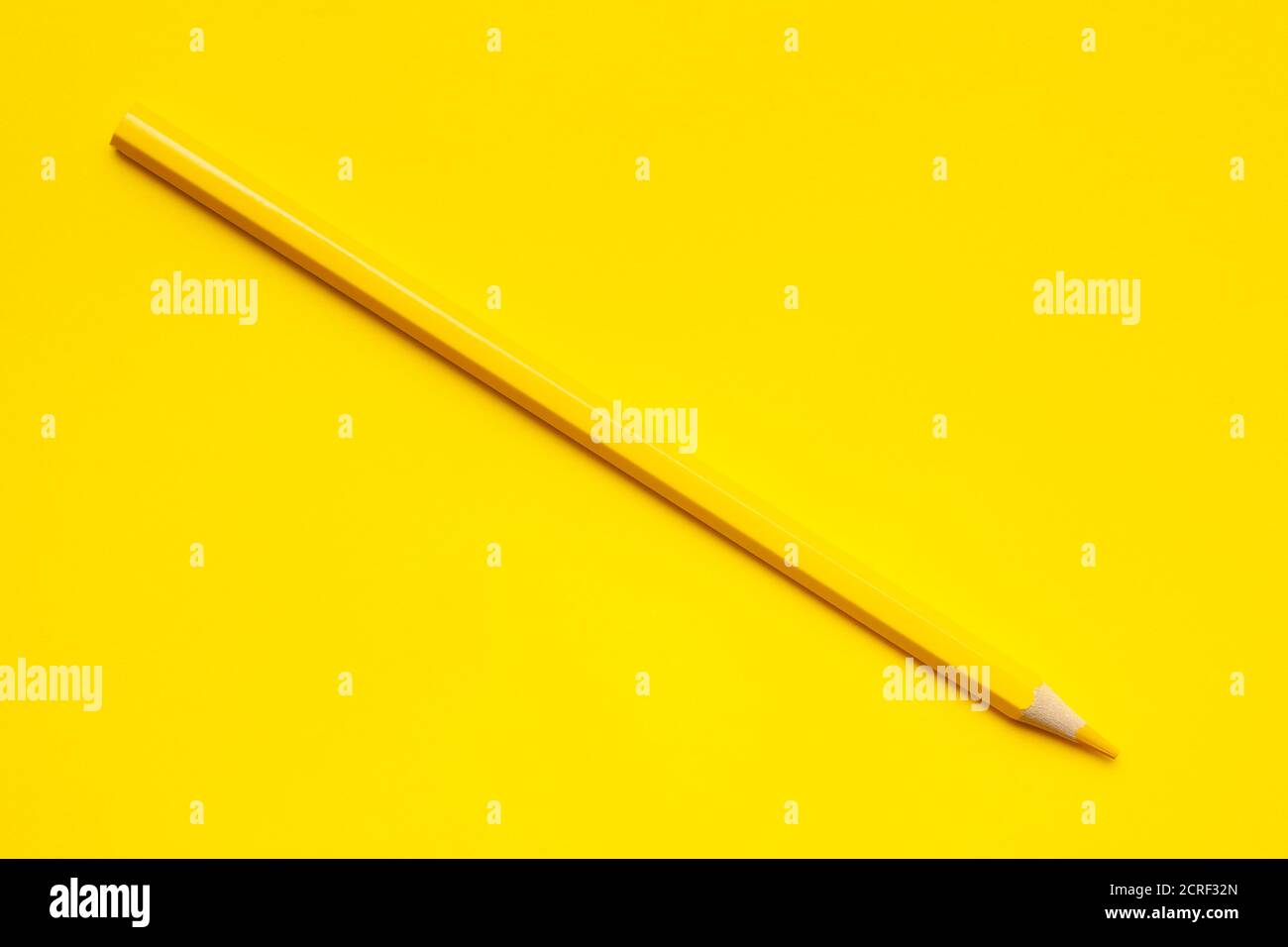 diagonal yellow sharp wooden pencil on a bright yellow background ...