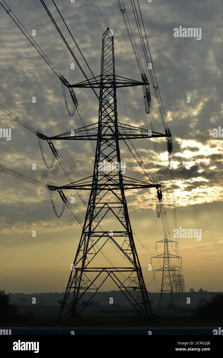 Electricity pylon transmission tower silhouette at sunrise with ...