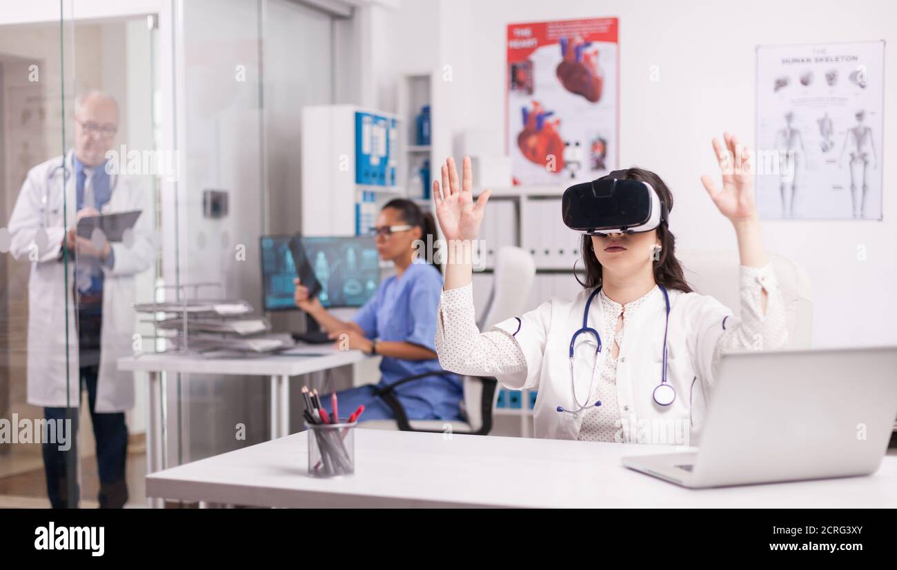 Young medic doing hand gesture wearing virtual reality headset in ...