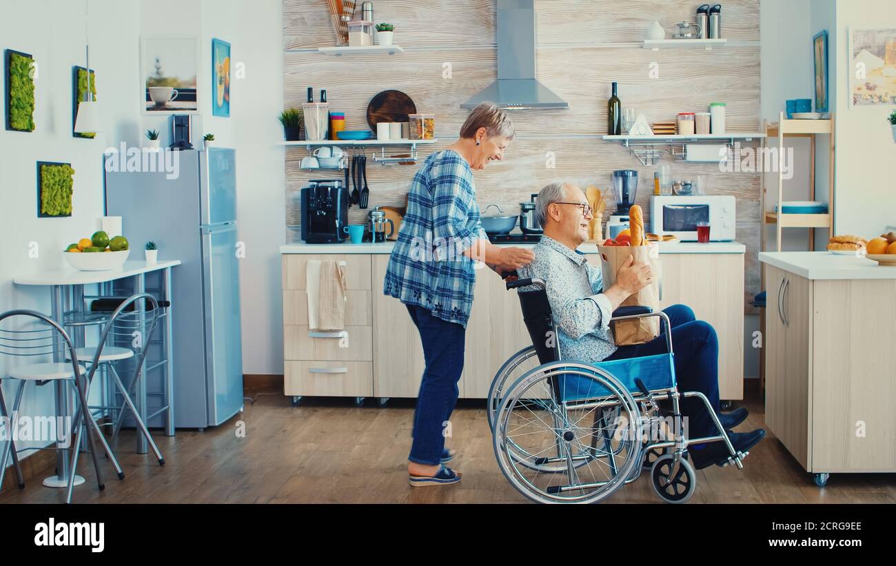 Old woman pushing invalid senior husband in wheelchair after arriving ...