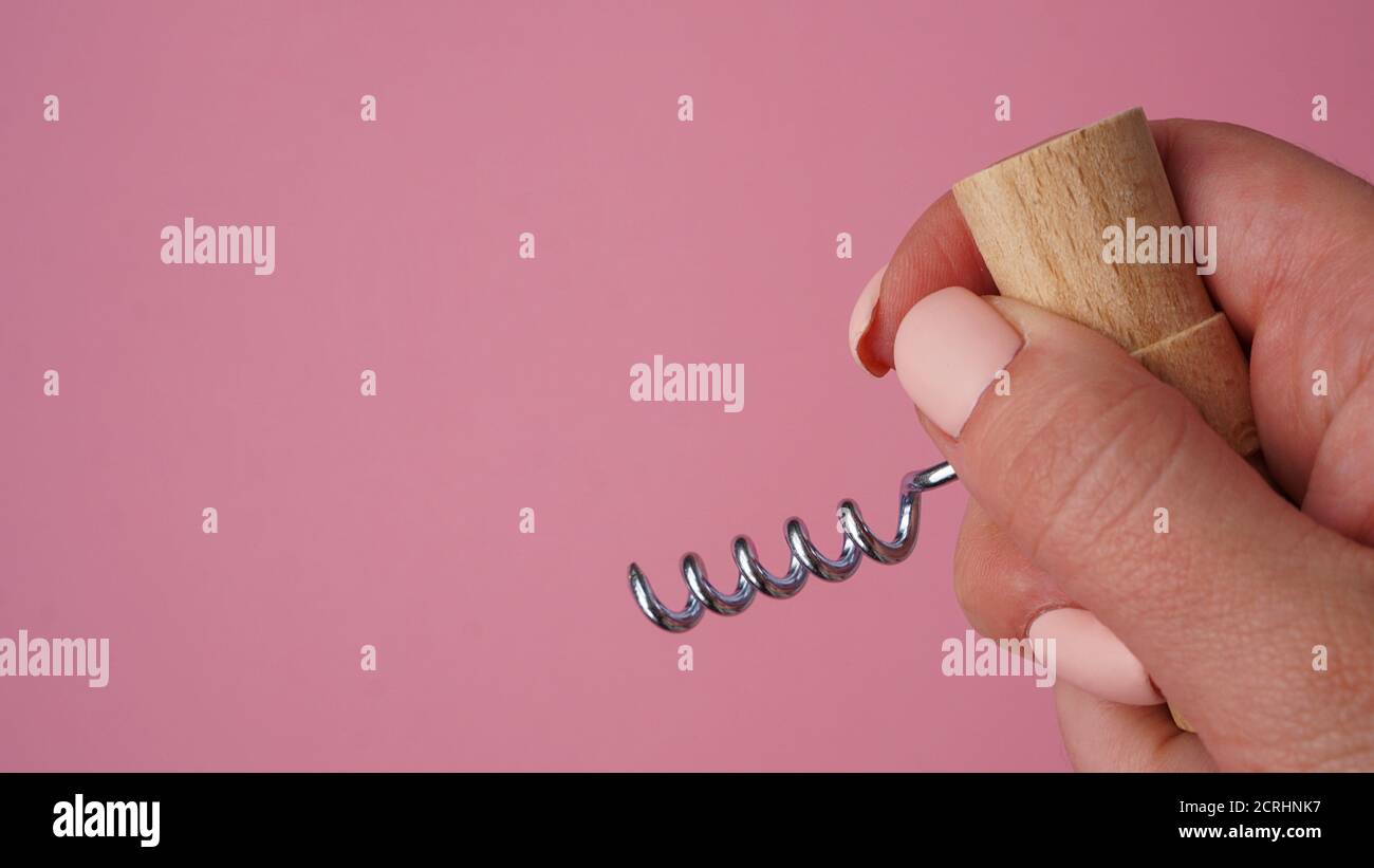 Female hand holding vintage corkscrew bottle opener over pink ...