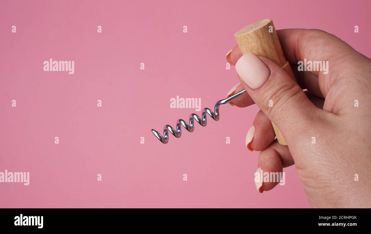 Female hand holding vintage corkscrew bottle opener over pink ...