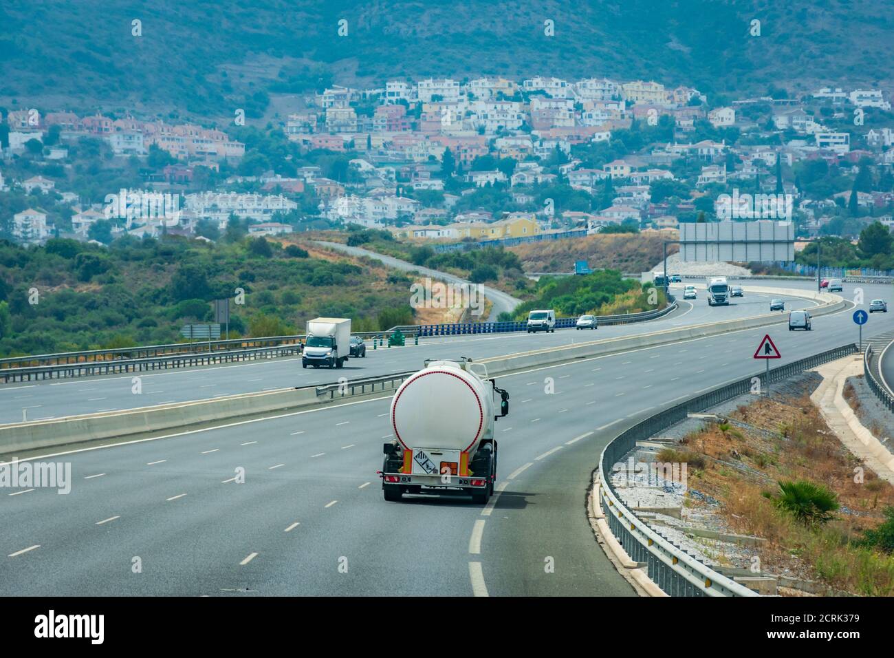 Dangerous goods tank truck driving on a multi-lane highway with traffic ...