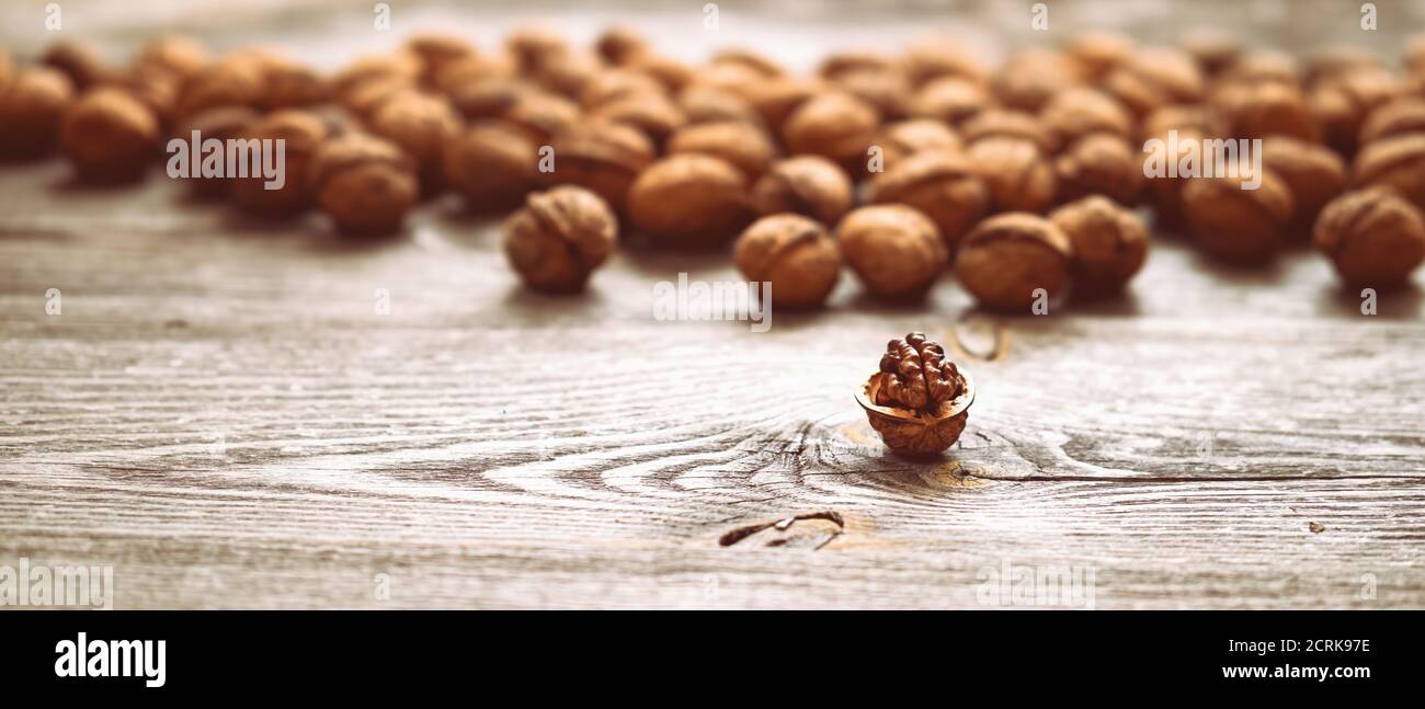 Heap of whole walnuts and one walnut kernel on wooden table - natural ...