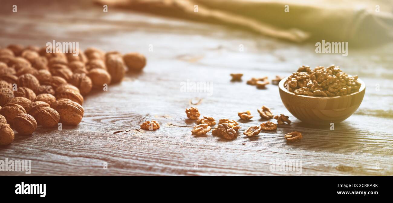 Fresh walnut kernels and whole walnuts in a bowl on rustic old wooden ...