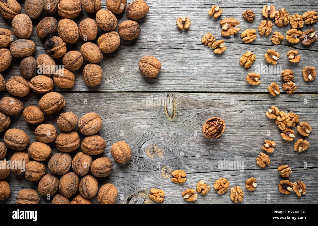 Heap of fresh walnut kernels and whole walnuts on wooden table ...