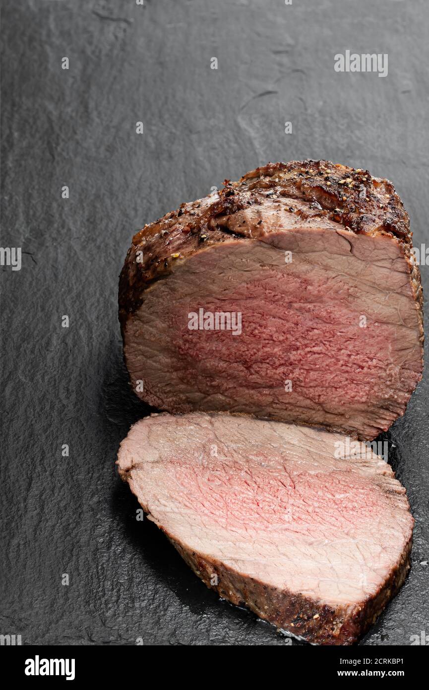 Roast beef on black stone background Stock Photo - Alamy