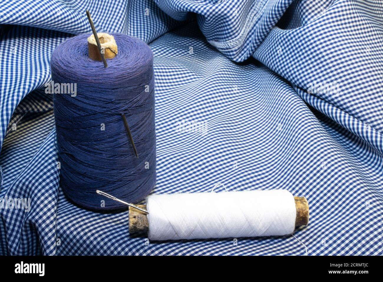 two spools of thread and needles on a piece of tartan Stock Photo - Alamy
