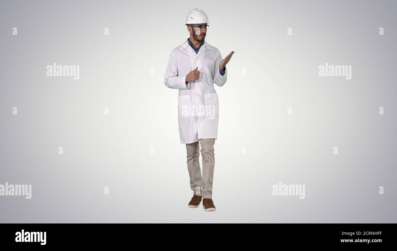 Scientist in white robe and helmet presenting pointing to side w Stock ...