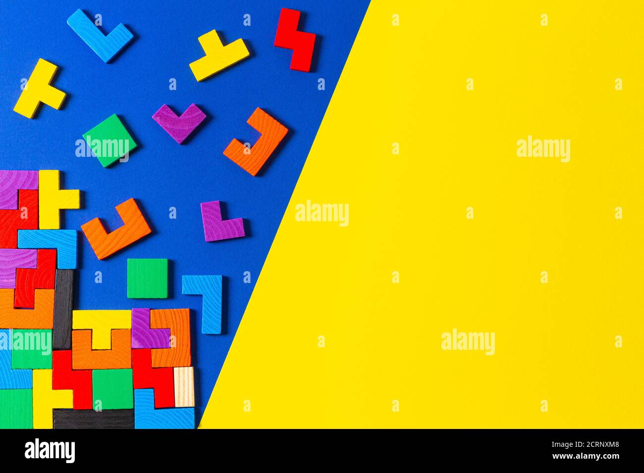 Different colorful shapes wooden puzzle blocks on blue and yellow ...