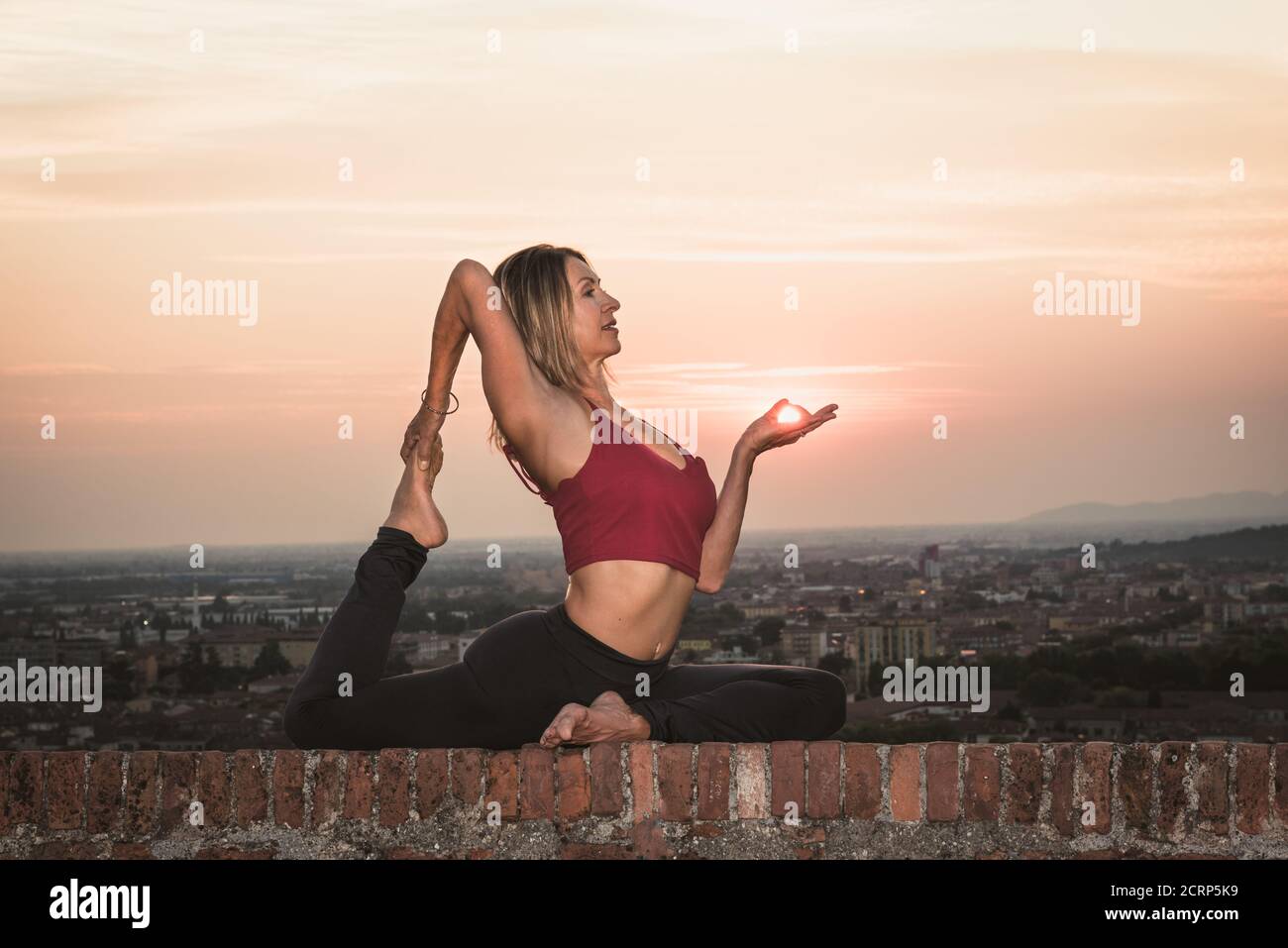 Front view of a back light of a faithful woman in yoga position holding ...