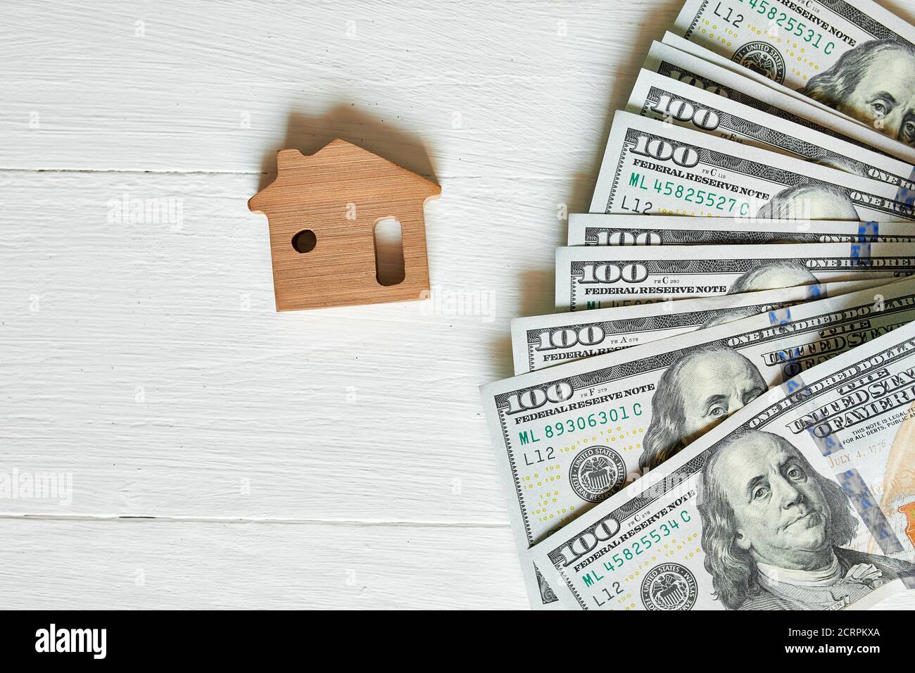 Small wooden house and hundred dollar on white background Stock Photo ...