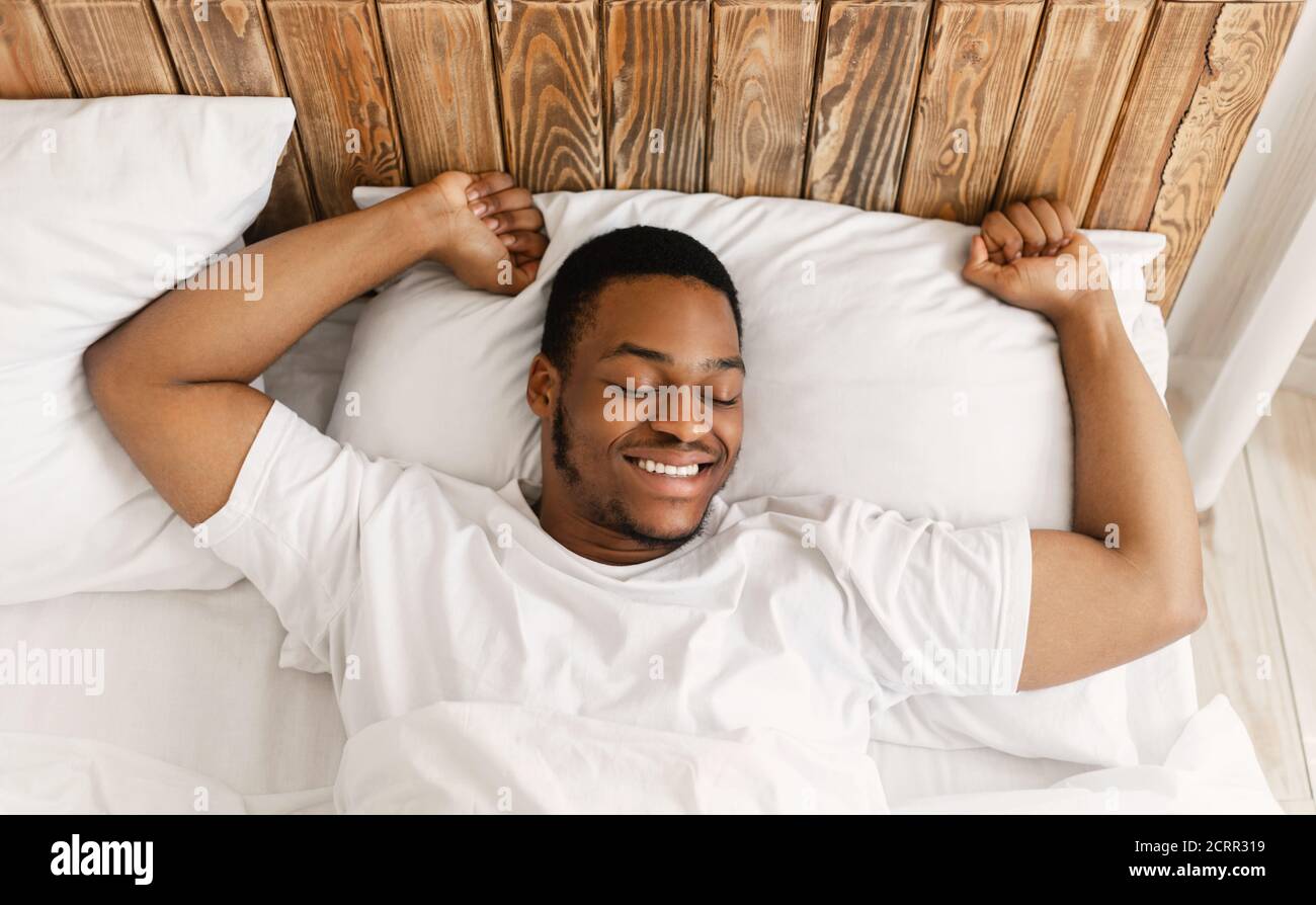 Rested African Man Waking Up Lying In Bed At Home Stock Photo - Alamy