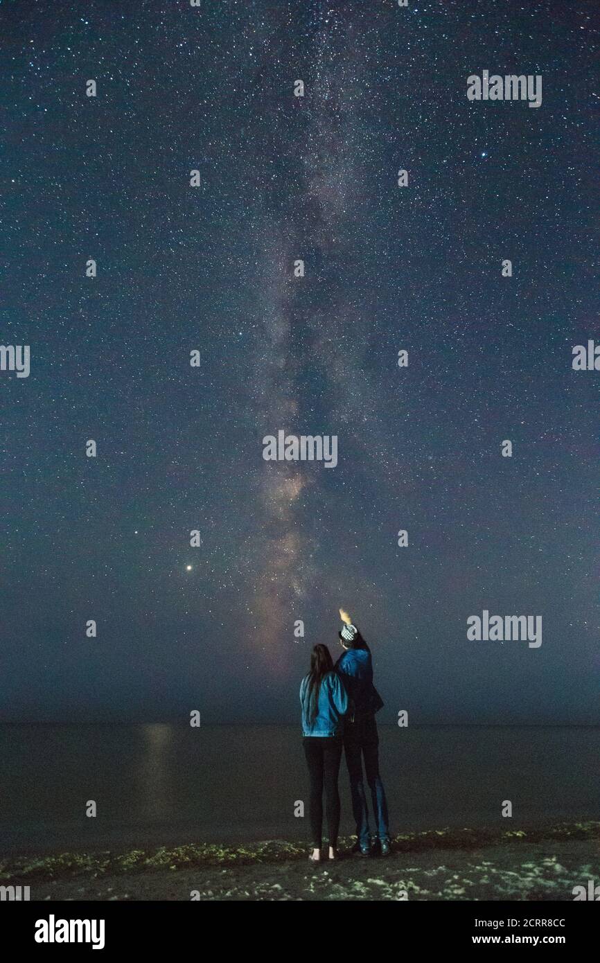 Guy showing starry sky to his girlfriend. Couple watching a night sky ...