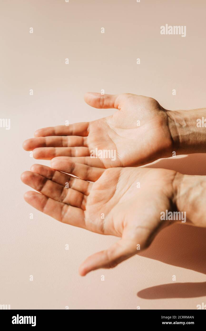Male hands outstretched forward, palms up on a pink background Stock ...