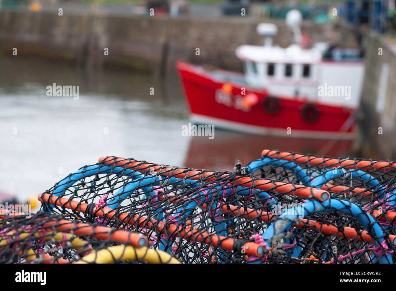 Stack of lobster pots with trawler in the background, Dunbar Harbour ...