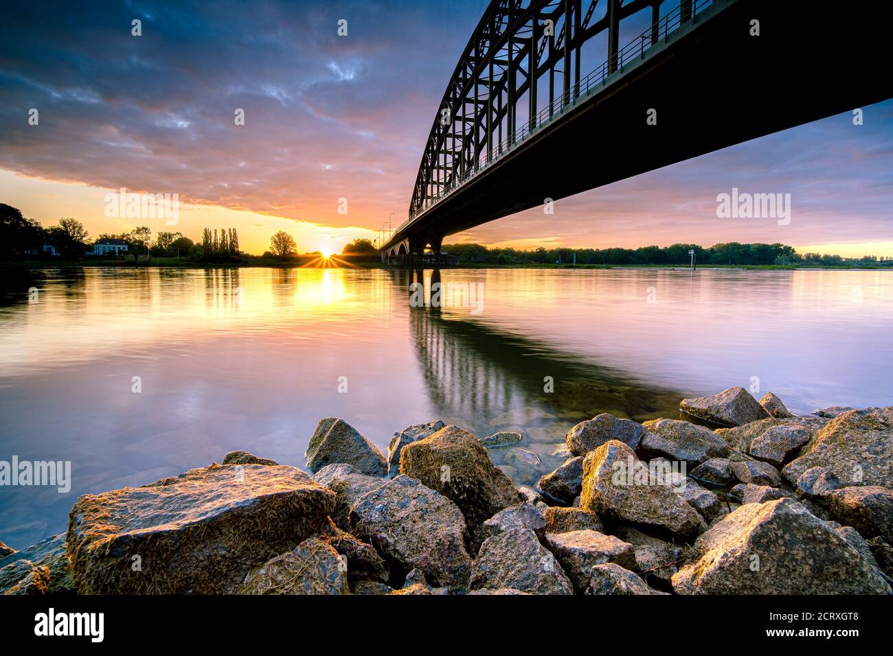 Striking arch bridge spans the river during the sunrise Stock Photo - Alamy