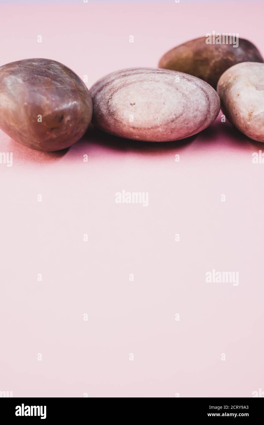 Vertical shot of pebbles isolated on a pink background Stock Photo - Alamy