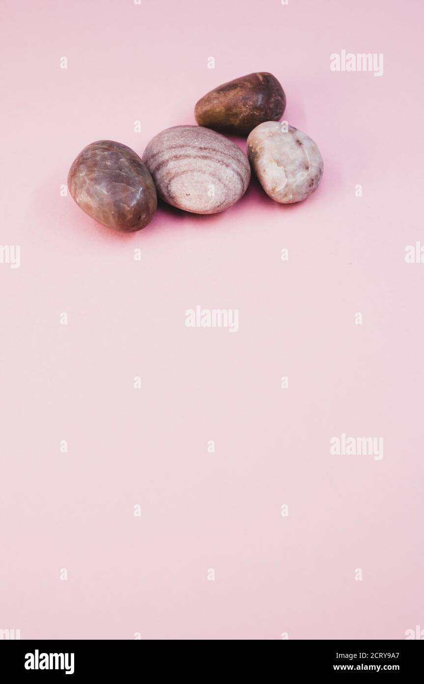 Vertical shot of pebbles isolated on a pink background Stock Photo - Alamy