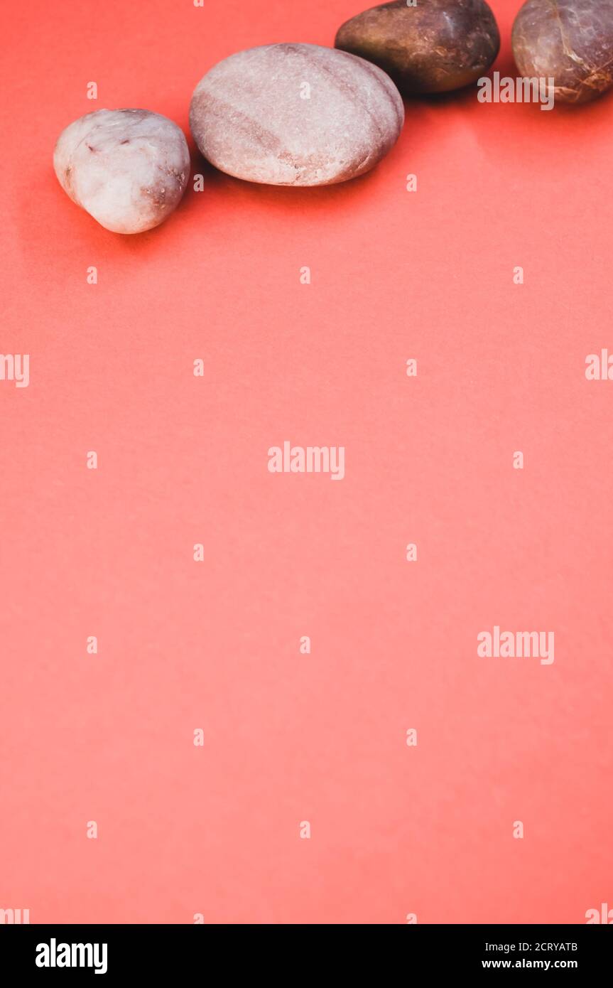 Vertical shot of pebbles isolated on a pink background Stock Photo - Alamy