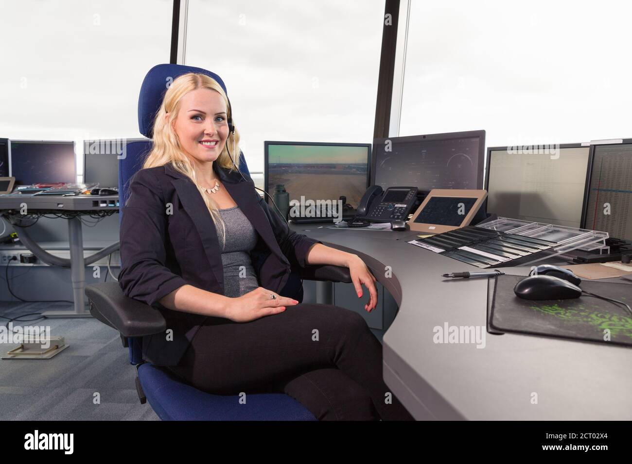 Female flight operations officer smiling for camera on chair in office ...