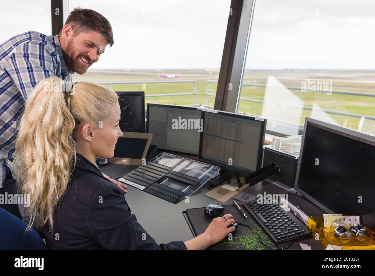 Man and woman using computer against window with airfield while working ...