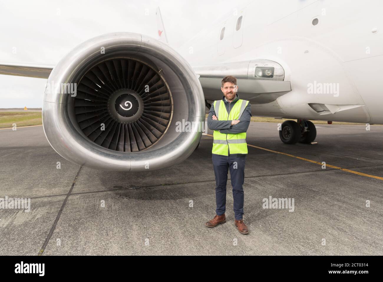 Full body man with crossed arms standing near aircraft turbine on ...