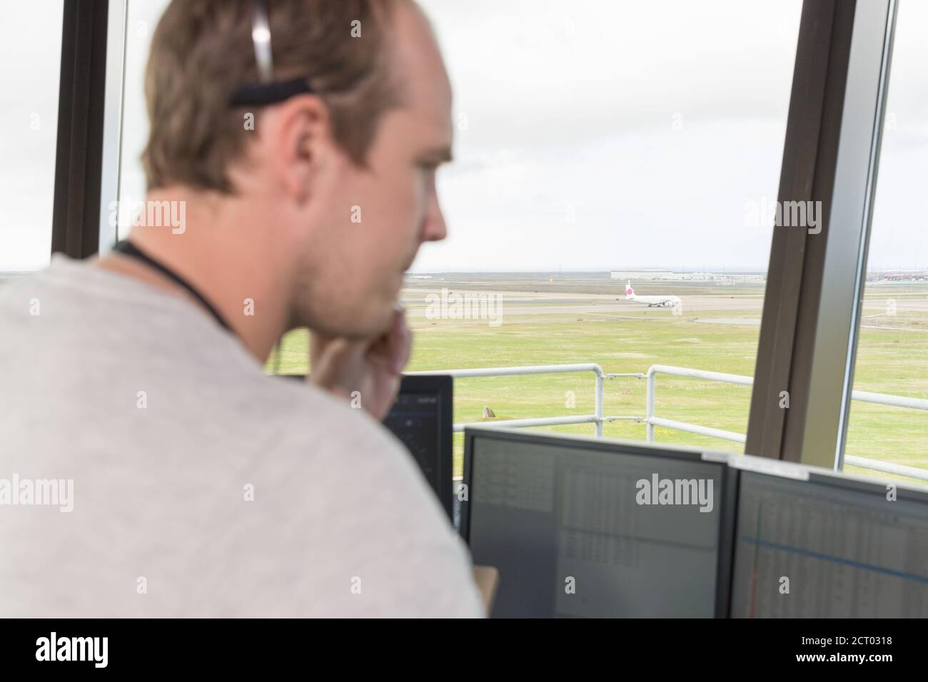 Flight operations officer standing near computers against window with ...