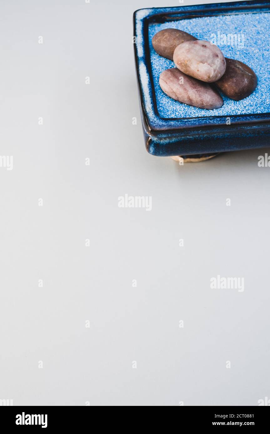 Vertical shot of pebbles on a rectangular box filled with small blue ...