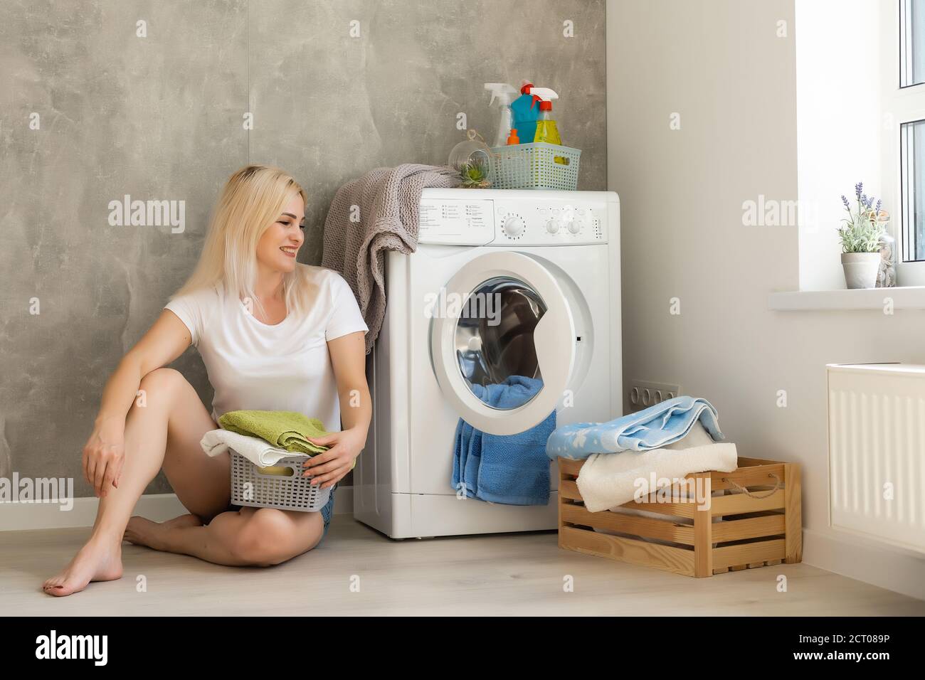 A young housewife with washing machine and clothes. Washing day Stock ...