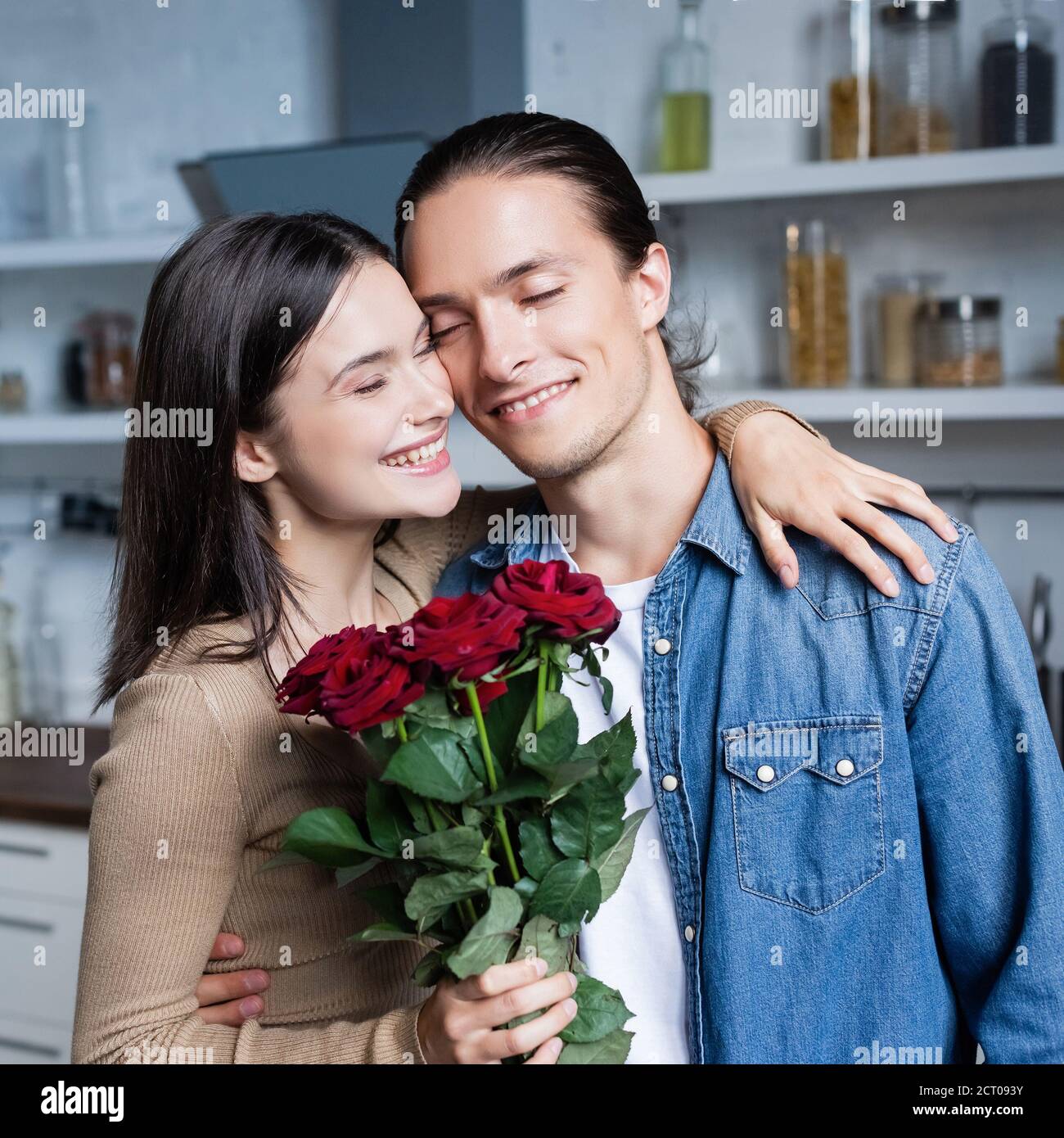 excited woman hugging boyfriend while holding bouquet of roses with ...