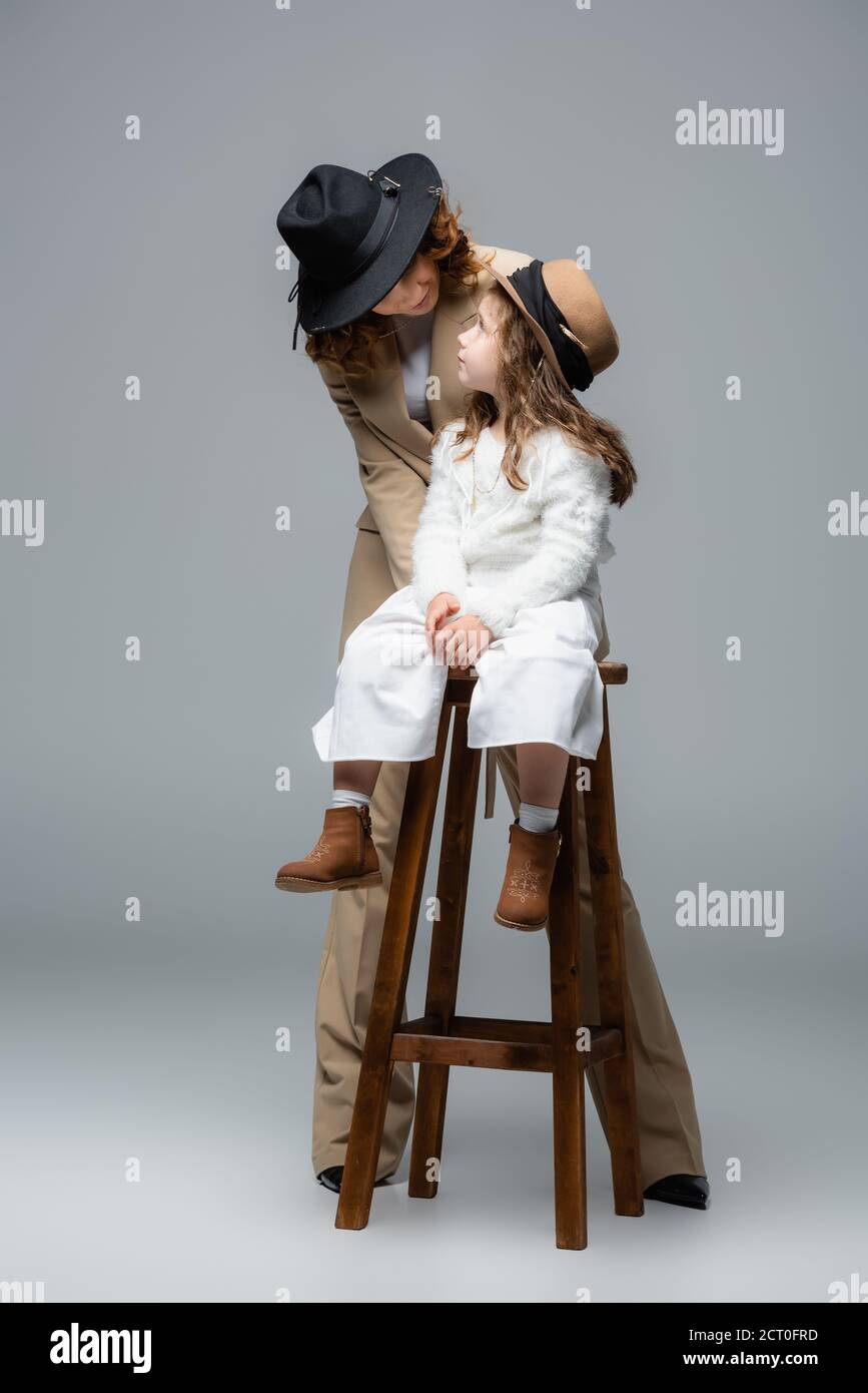 elegant mother posing near daughter on chair on grey Stock Photo - Alamy