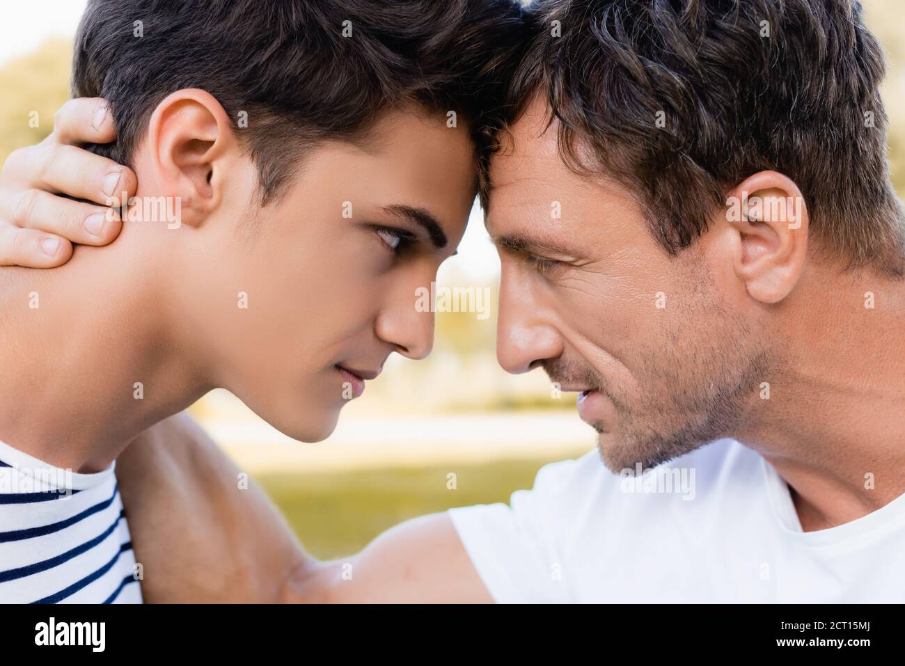 side view of serious father and teenager son looking at each other ...