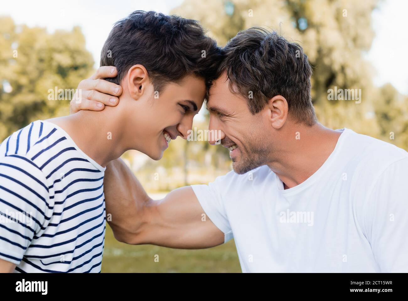 side view of joyful father and teenager son looking at each other Stock ...