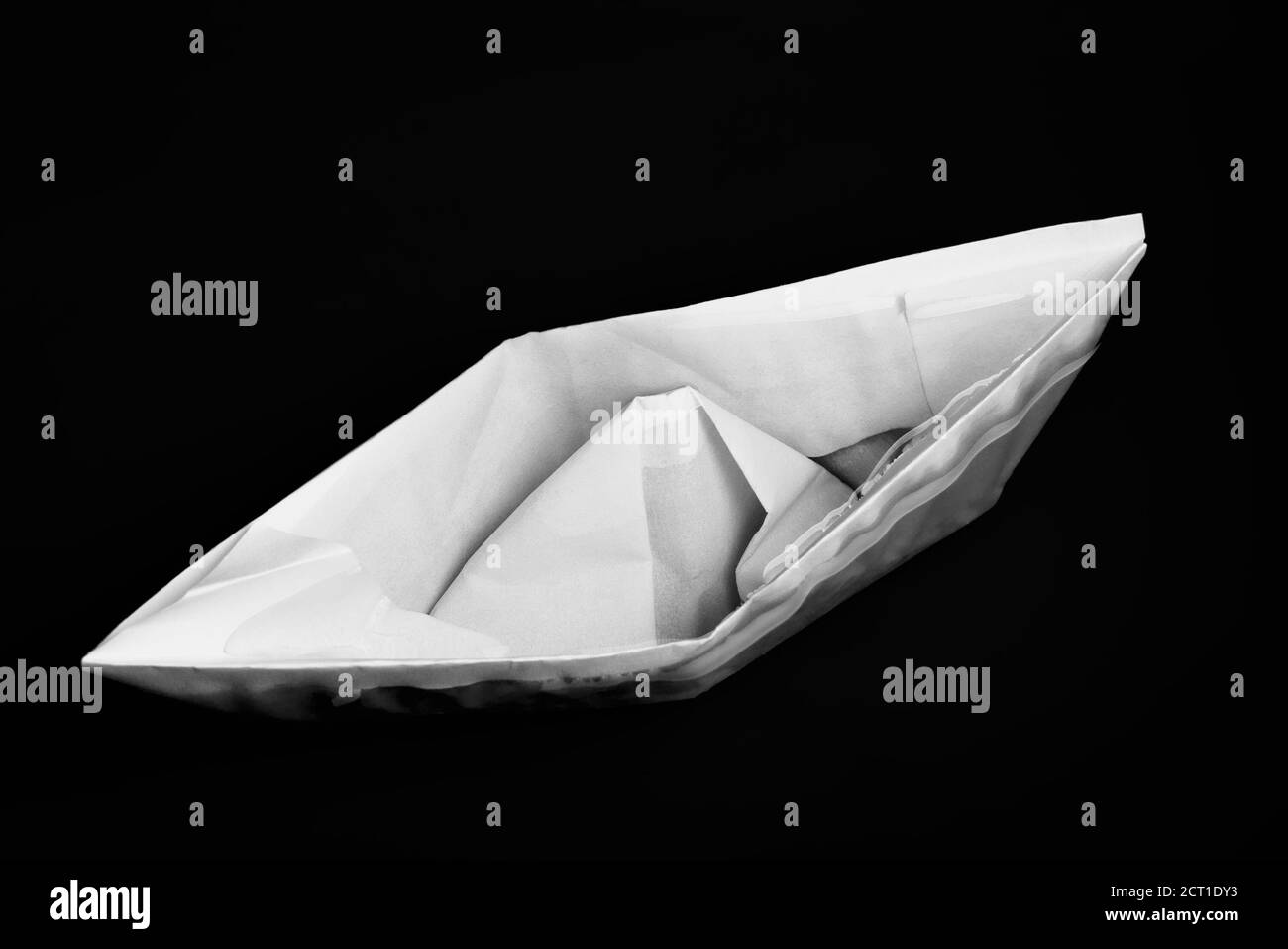 Closeup of sinking folded paper ship against black background with ...