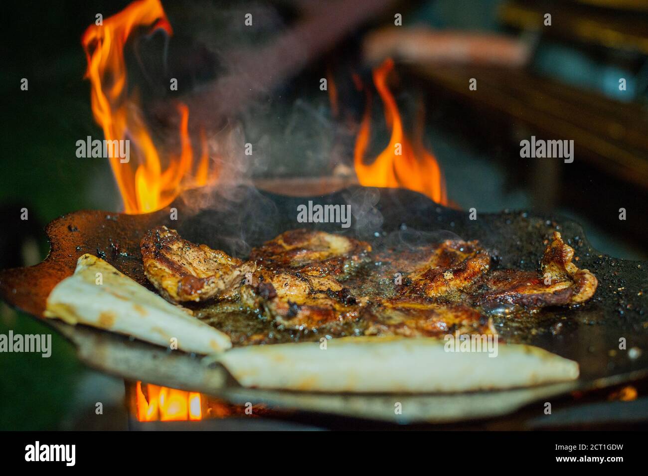 Fresh cut bacon being cooked over a campfire. Meat in a frying pan over ...