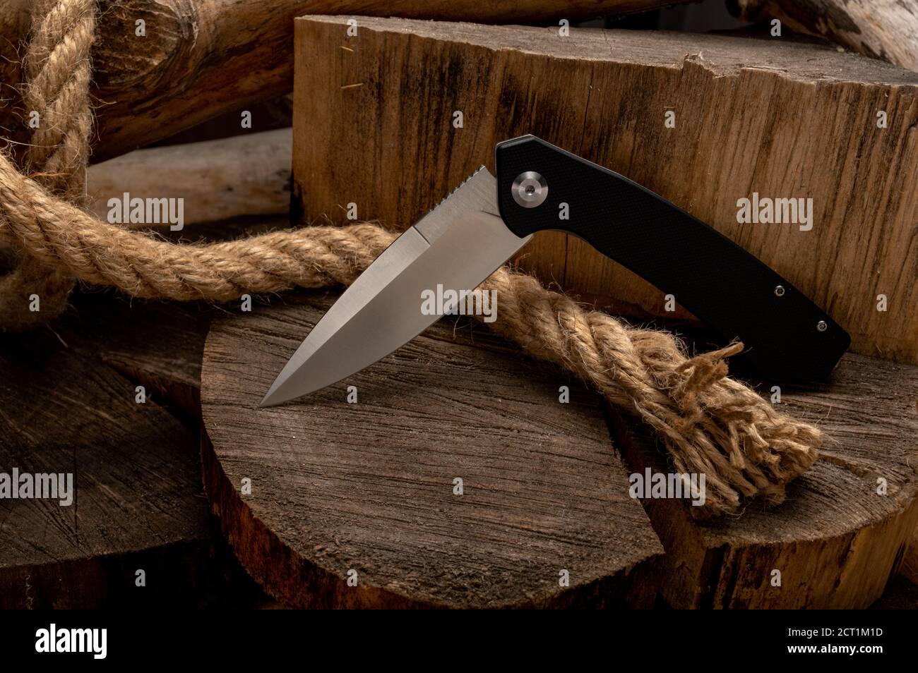 Knife with a black handle in a bent position. A folding knife on a tree ...