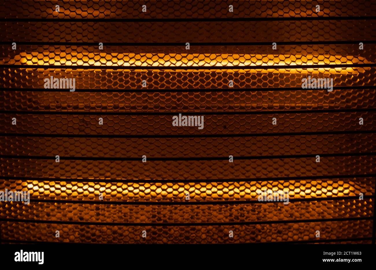Bars of illuminated electric heater glowing orange and gold through ...