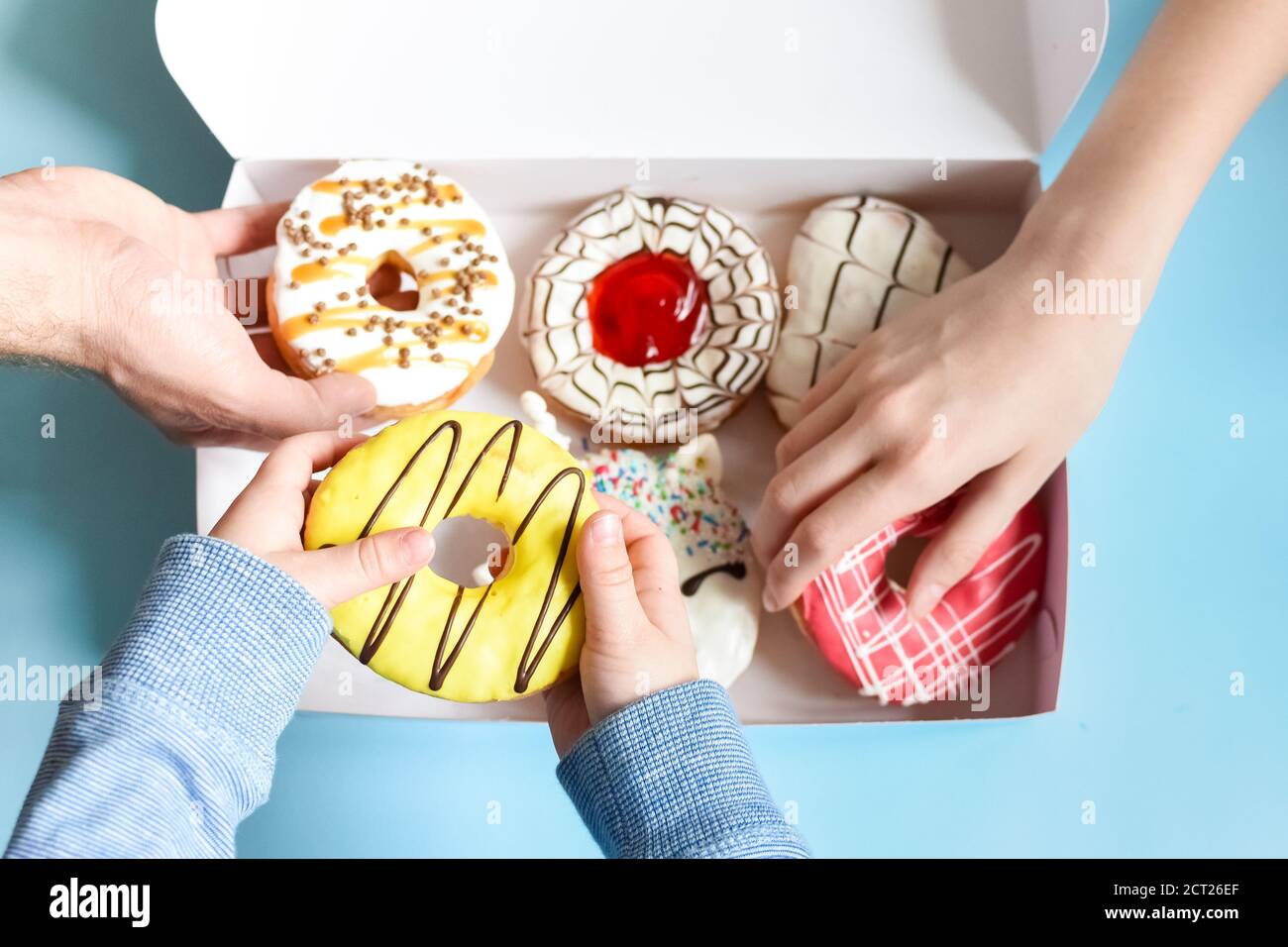 People hands takes donuts from donuts box over blue background. Family ...