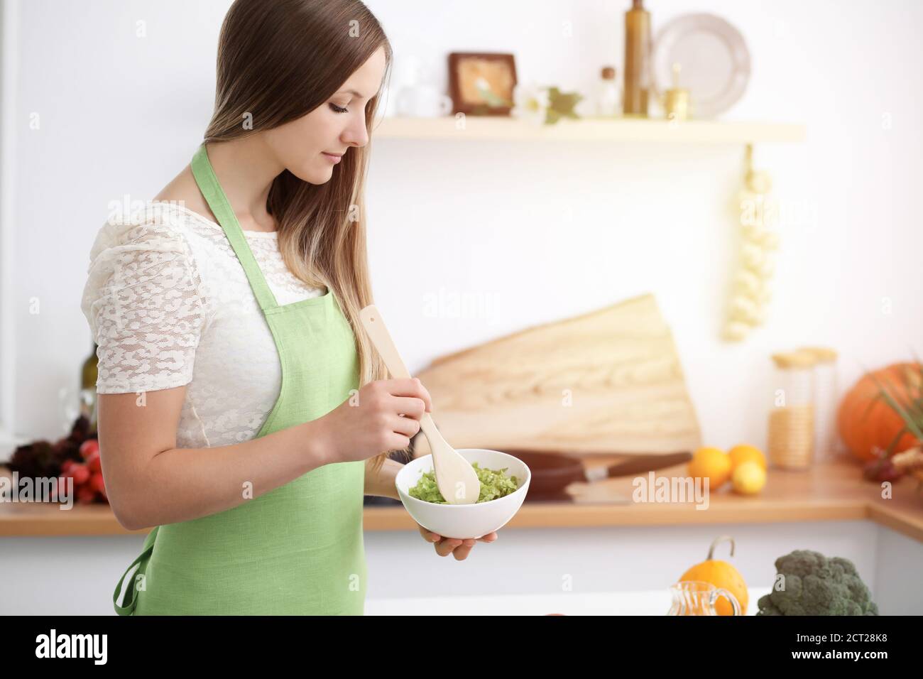 Beautiful woman dressed in apron is cooking meal in sunny kitchen Stock ...