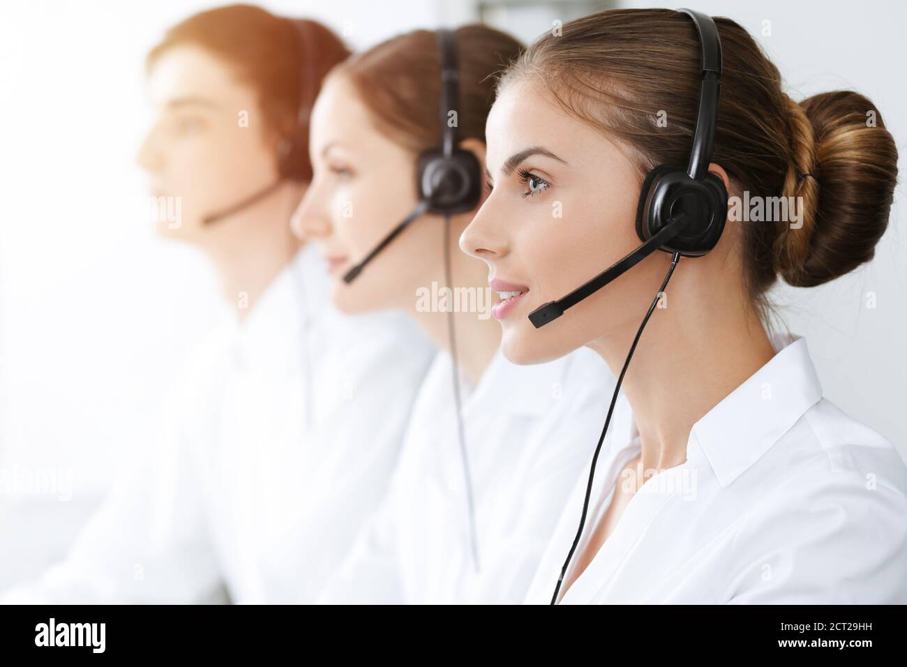 Call center. Beautiful young woman using headset and computer to help ...