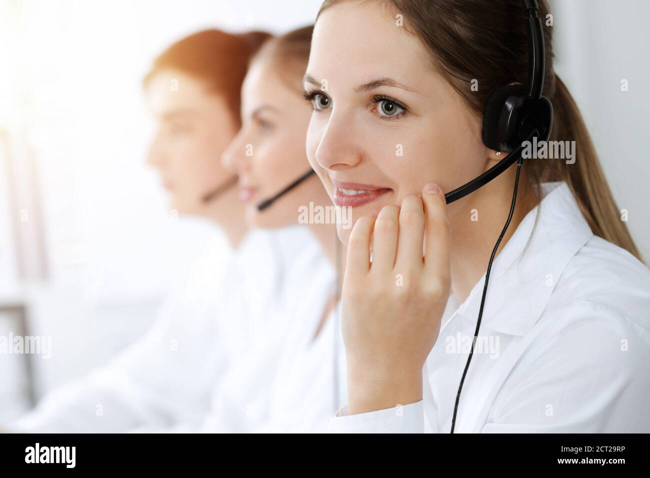 Call center. Beautiful young woman using headset and computer to help ...