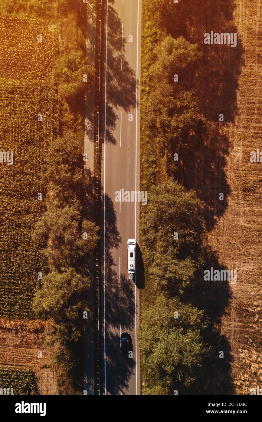 Aerial view of minibus and car on road through countryside, top view ...