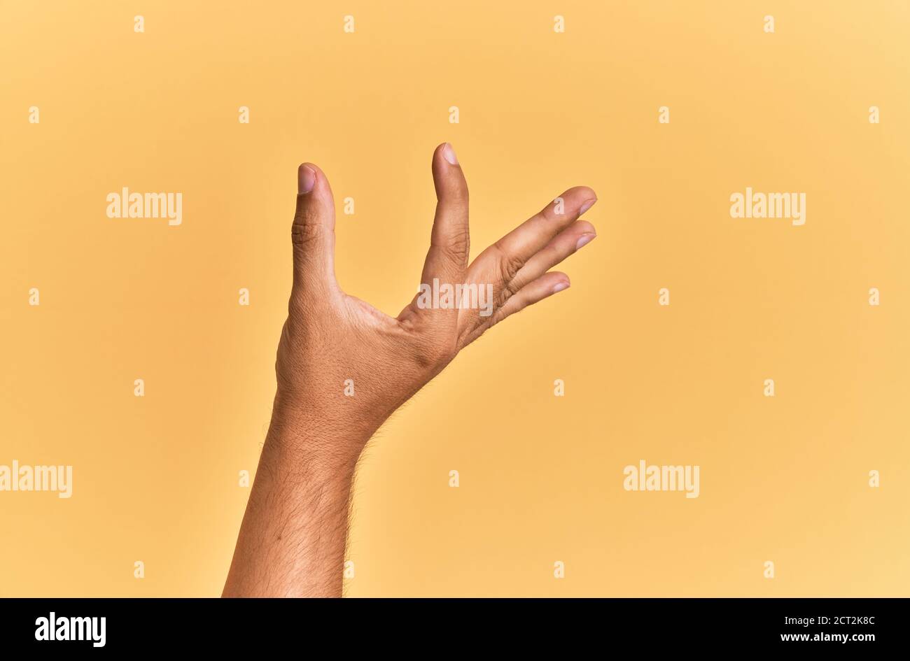 Arm and hand of caucasian man over yellow isolated background picking ...