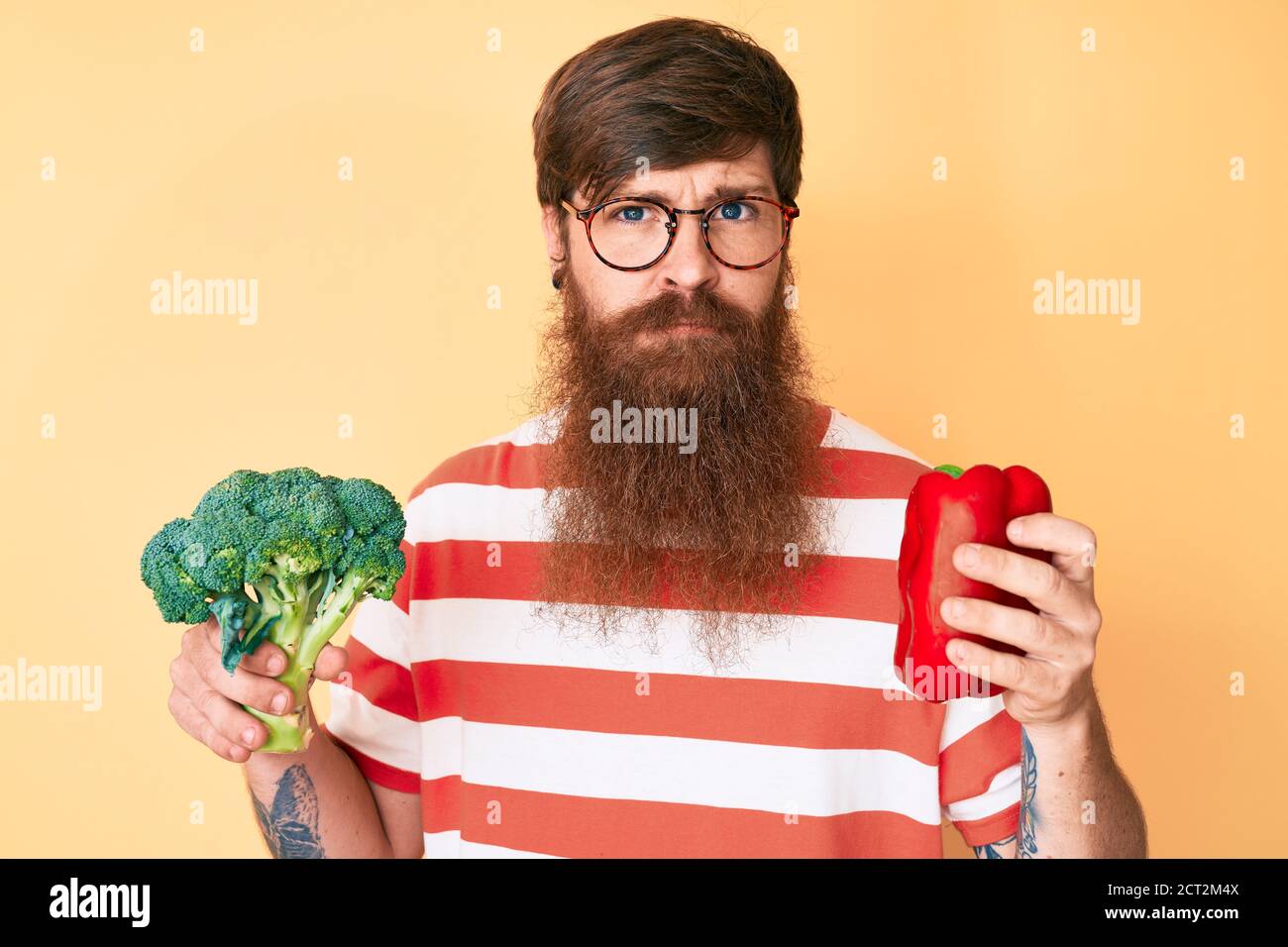 Handsome young red head man with long beard holding broccoli and red ...