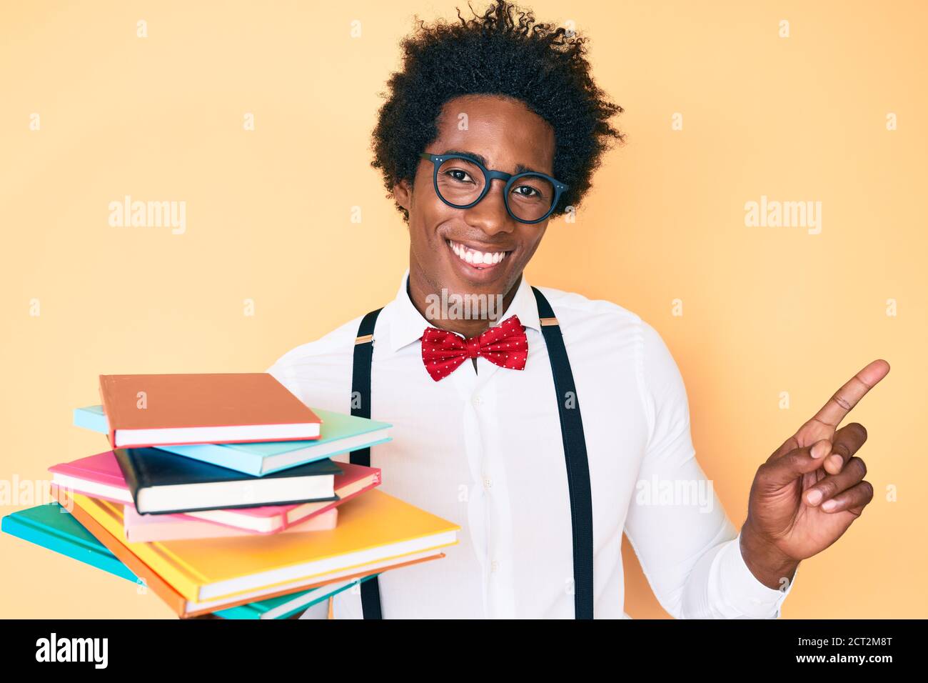 Handsome african american nerd man with afro hair holding books smiling ...