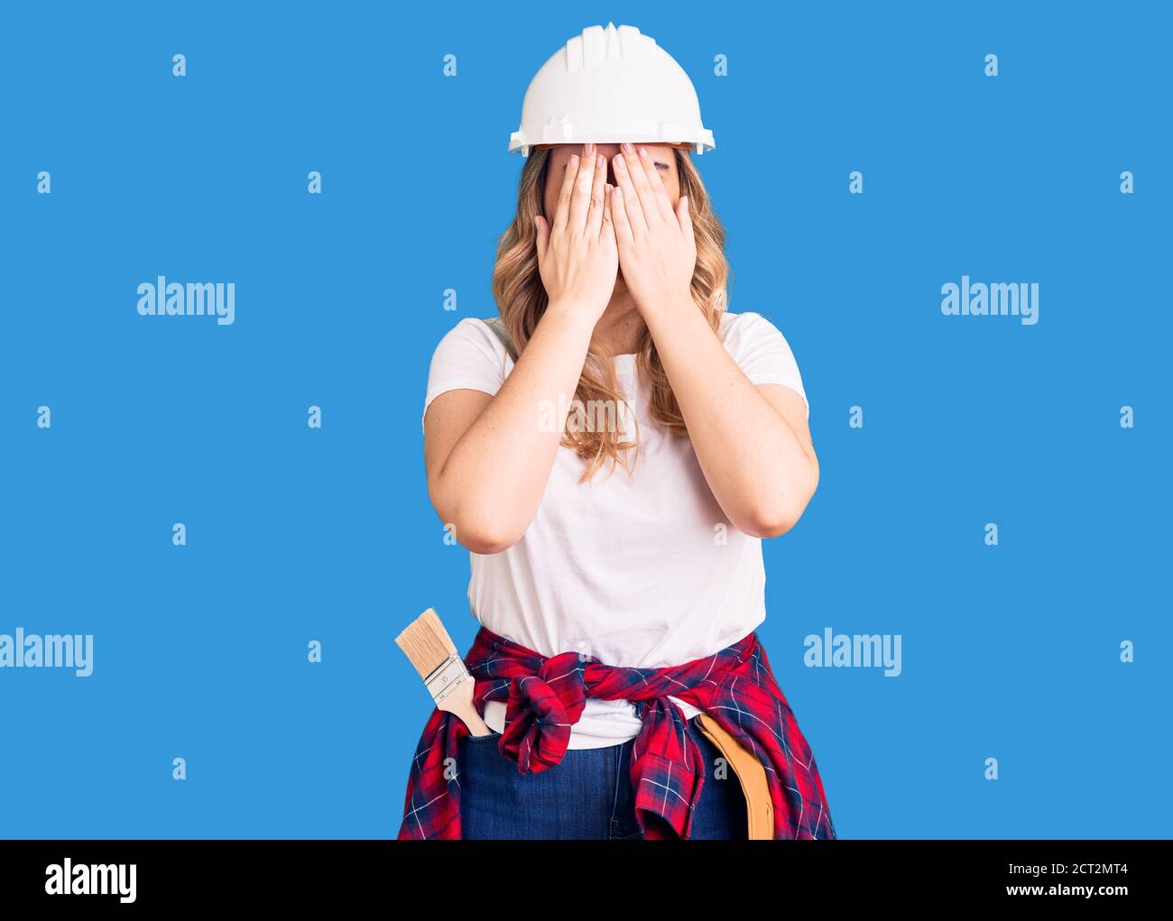 Young caucasian woman wearing security helmet with sad expression ...