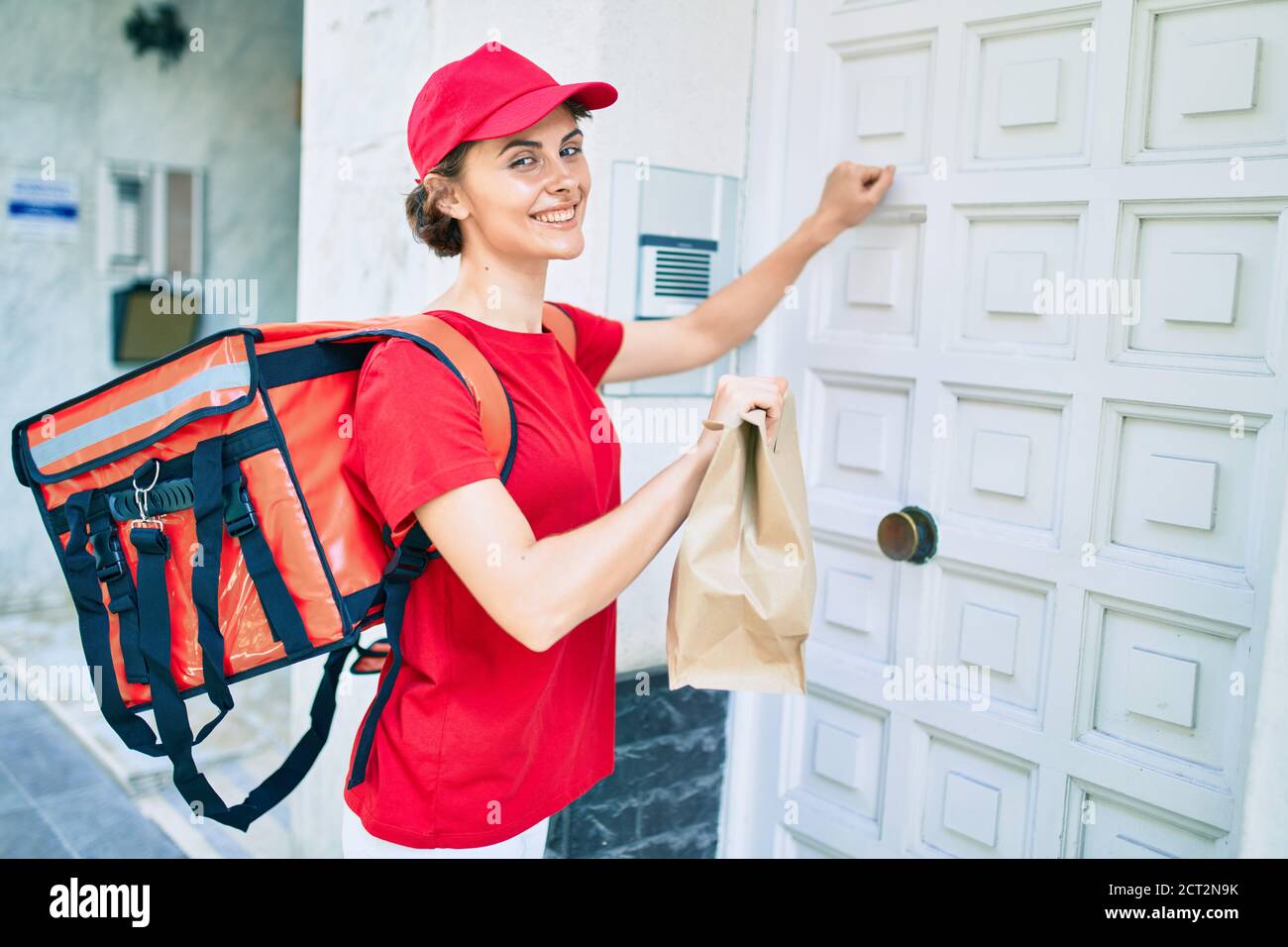 Delivery business worker woman wearing uniform smiling happy knocking ...