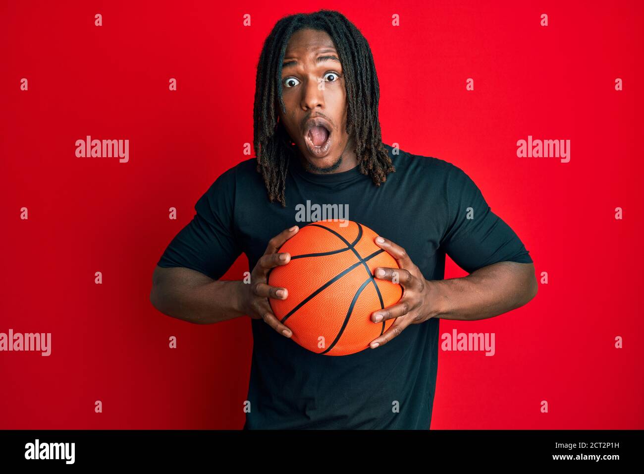 African american man with braids holding basketball ball afraid and ...