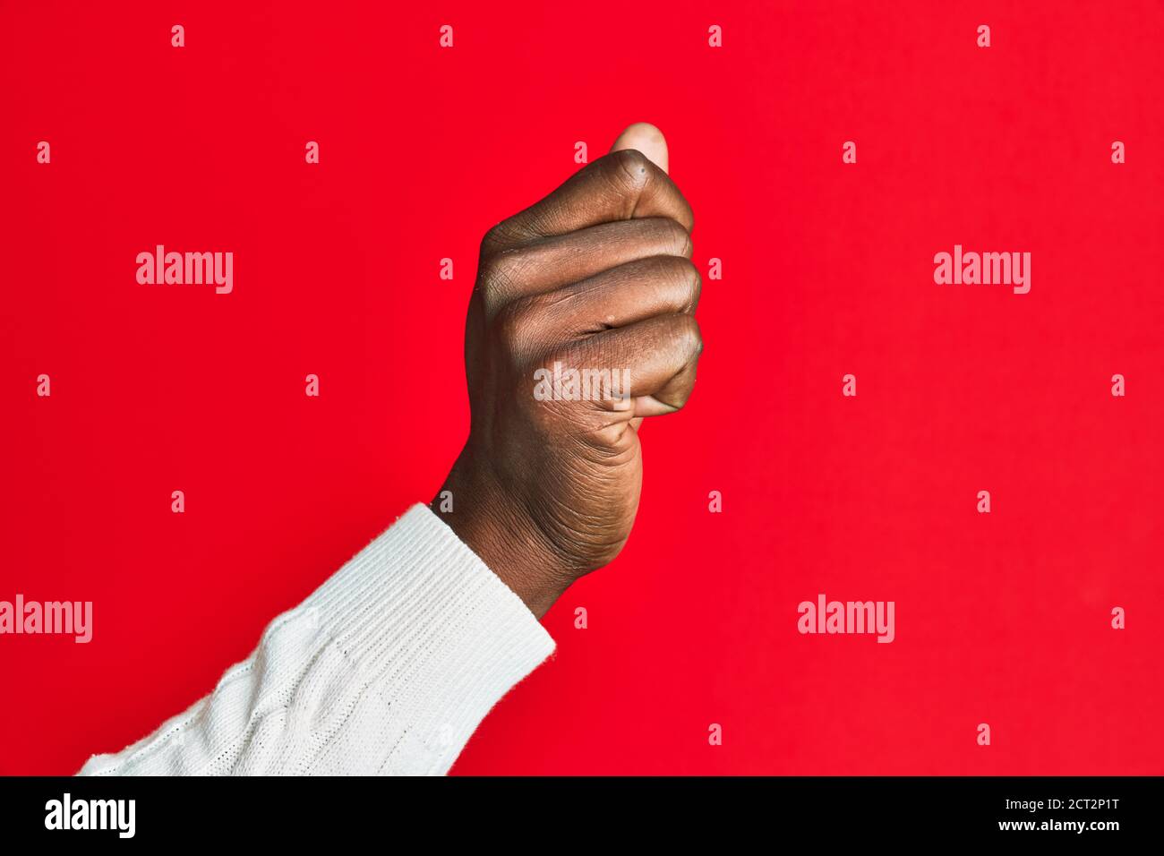Arm and hand of african american black young man over red isolated ...